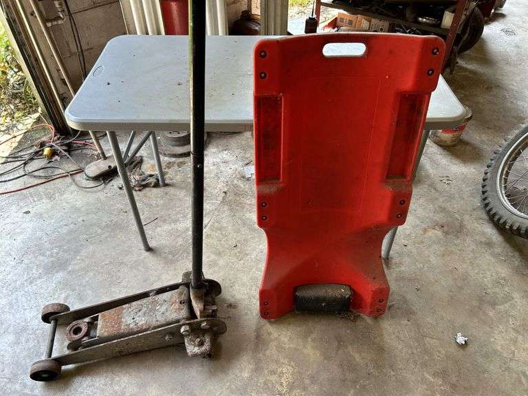 Red Plastic Mechanic’s Creeper and Rusted Hydraulic Car Jack ...