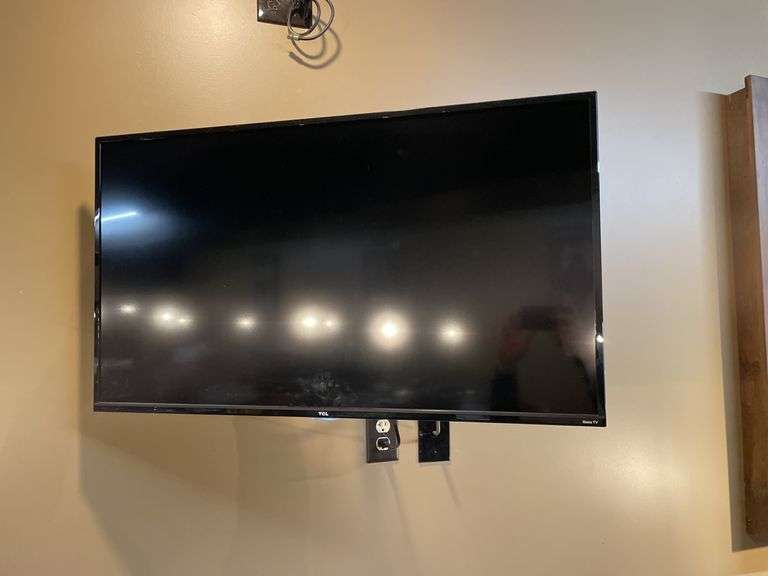 TCL 40 inch Roku TV. Powered on. Mounted to the wall includes bracket ...