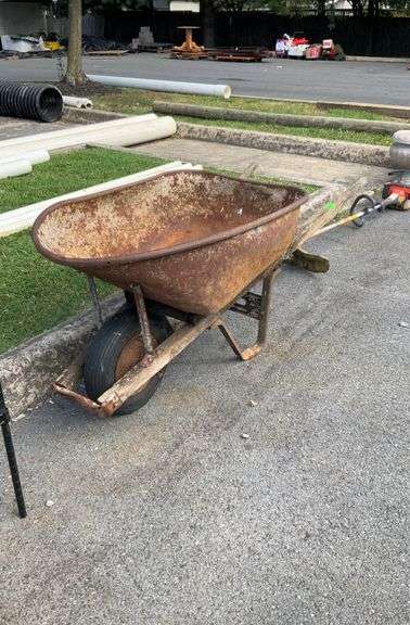 Wheelbarrow, metal hopper, two wooden handles, rusty and dented, tire ...