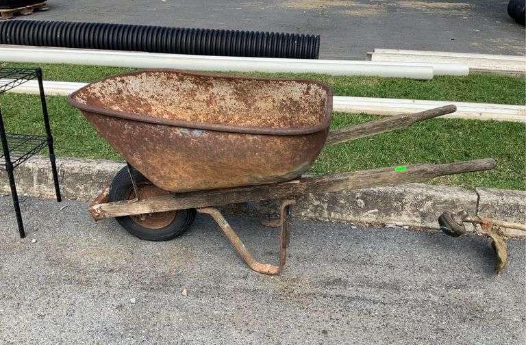 Wheelbarrow, metal hopper, two wooden handles, rusty and dented, tire ...