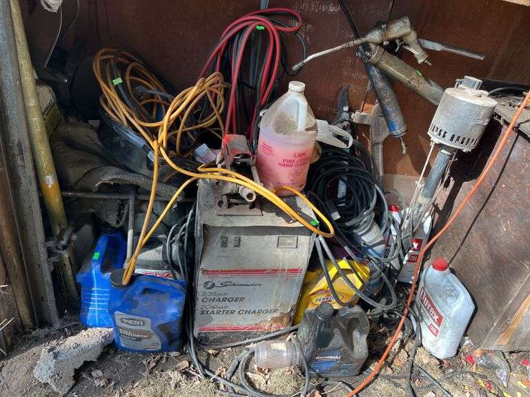 Battery charger, grease guns, electric cords, misc contents of corner ...