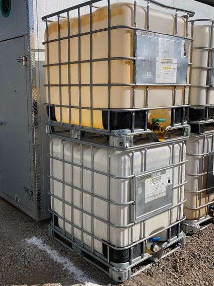 (2) 275 gallon liquid containers with protective metal cage and drain ...